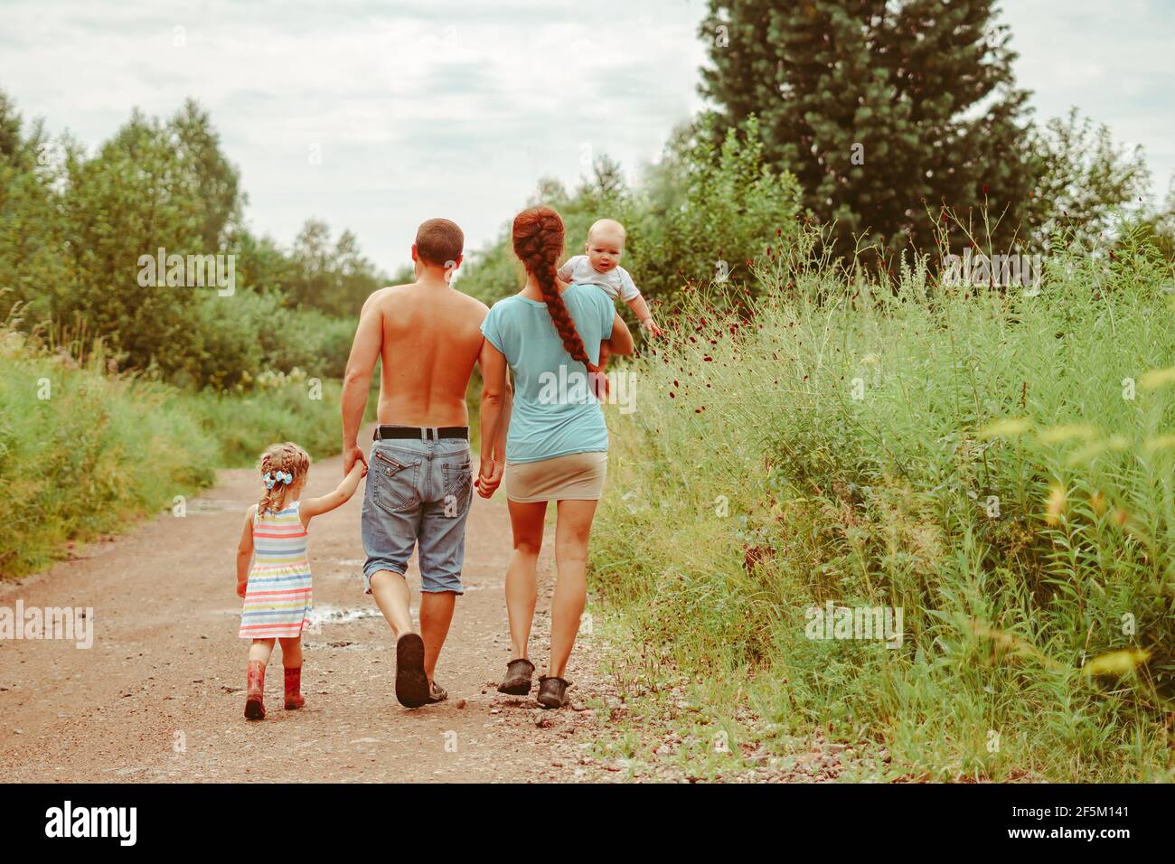 Family walking on path holding hands smiling Stock Photo - Alamy