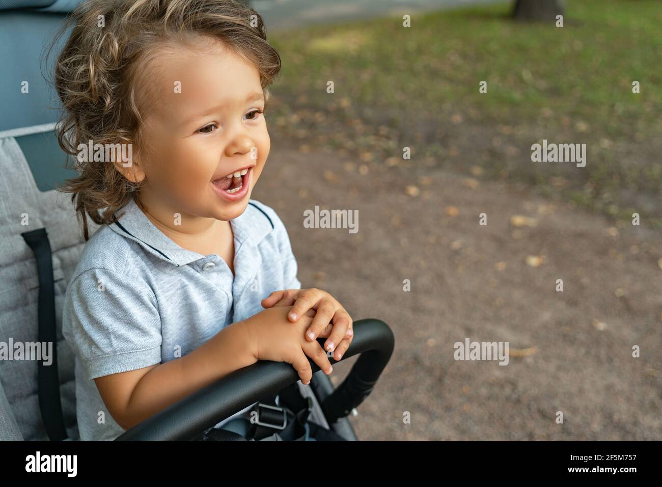 Portrait of a little joyful and laughing long-haired child sitting in a ...