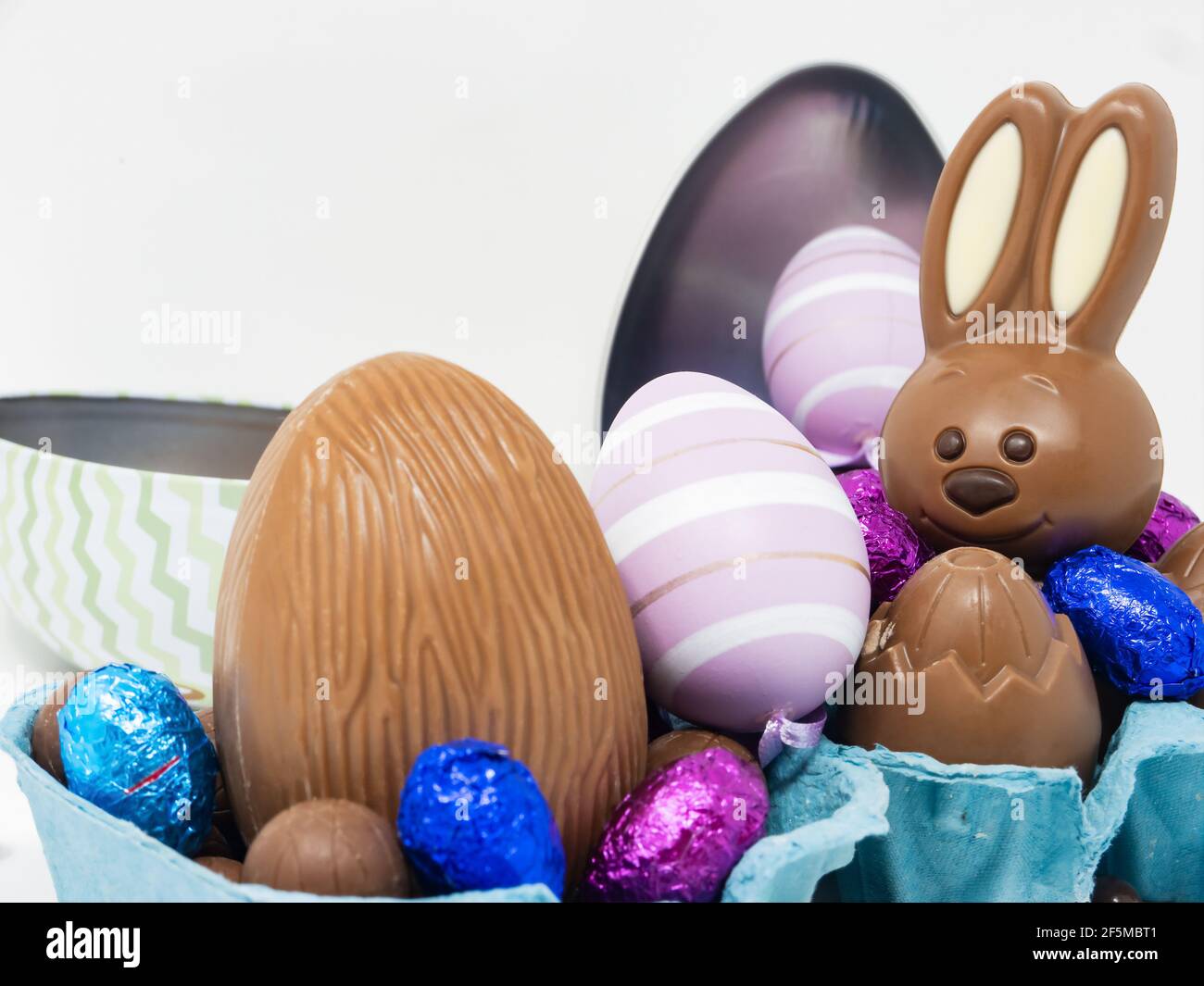 Happy chocolate Easter bunny among chocolate Easter eggs on a white ...