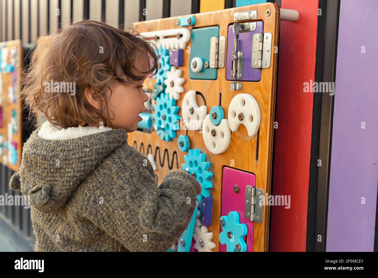 Portrait of a modern little boy playing with a busy board outdoors in ...