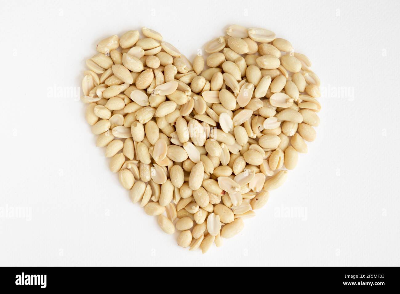 Salted peeled peanuts in a heart shape isolated on white background ...