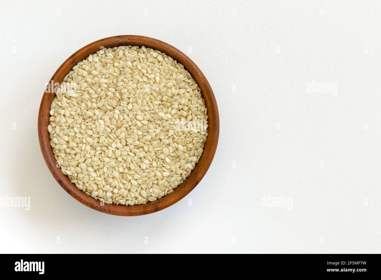 White sesame seeds in wooden bowl flat lay isolated on white background ...