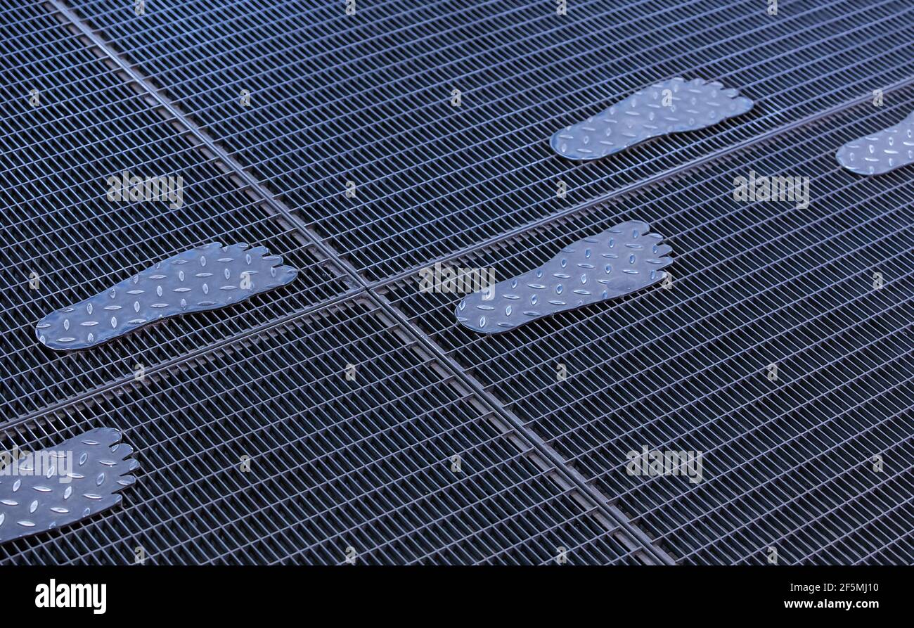 imprints of human feet made of metal on a metal mesh surface Stock ...