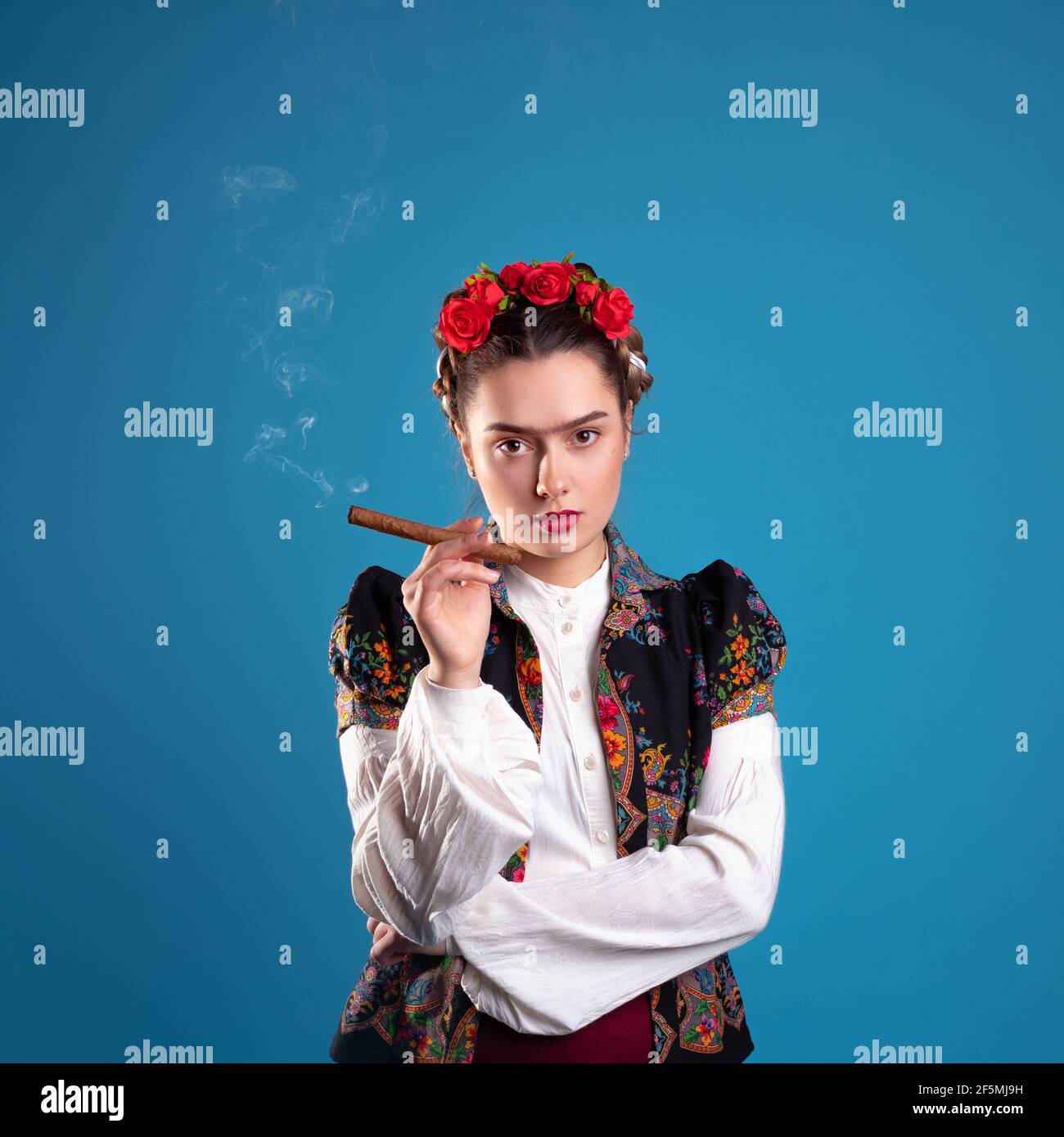 Young woman in the image of the Mexican artist Frida with red roses in ...
