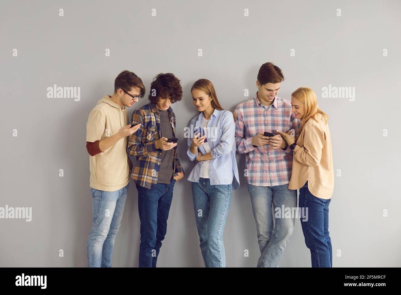 Group of happy young people using mobile phones, chatting and sharing ...