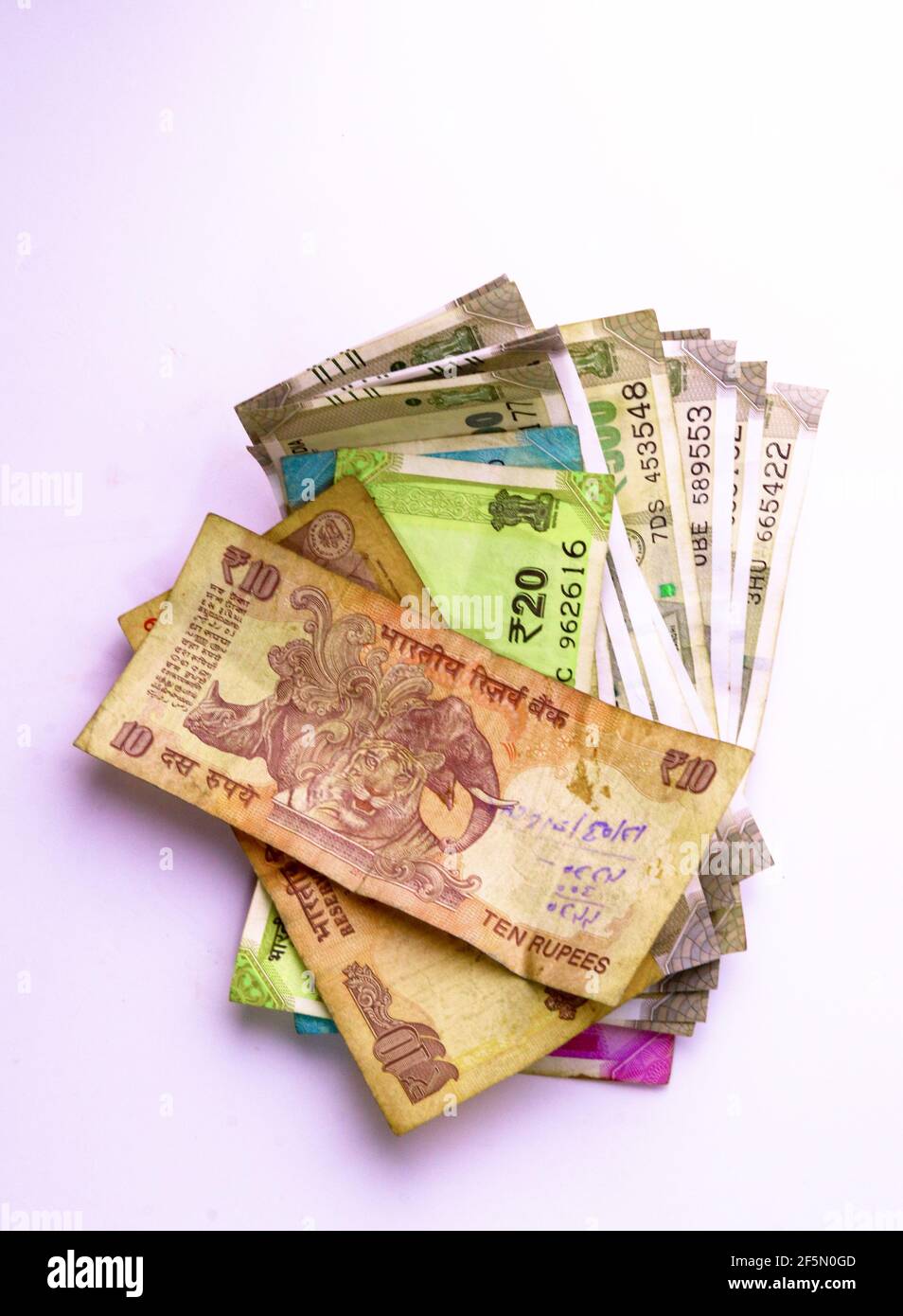 Vertical shot of Indian rupee banknotes isolated on a light purple ...