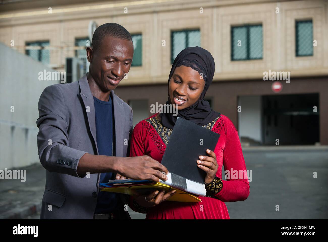 young businessman standing in the street checking his partner's folder ...