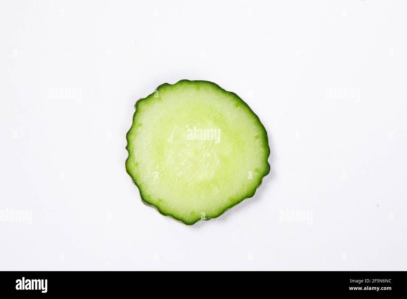 Closeup shot of a single cucumber slice isolated on white background ...