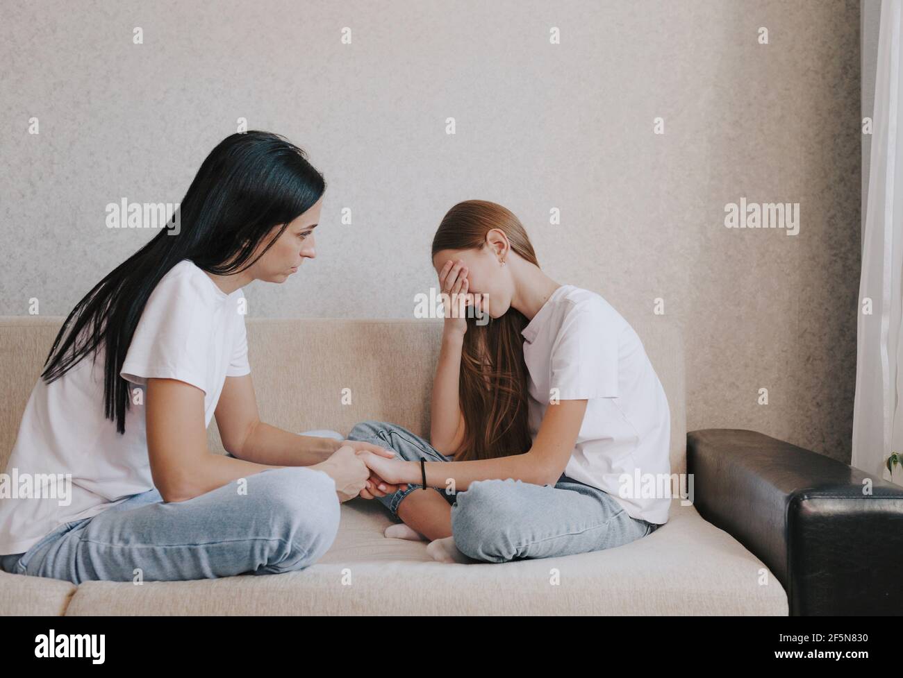 a loving mother holds her hand and calms her distressed daughter Stock ...