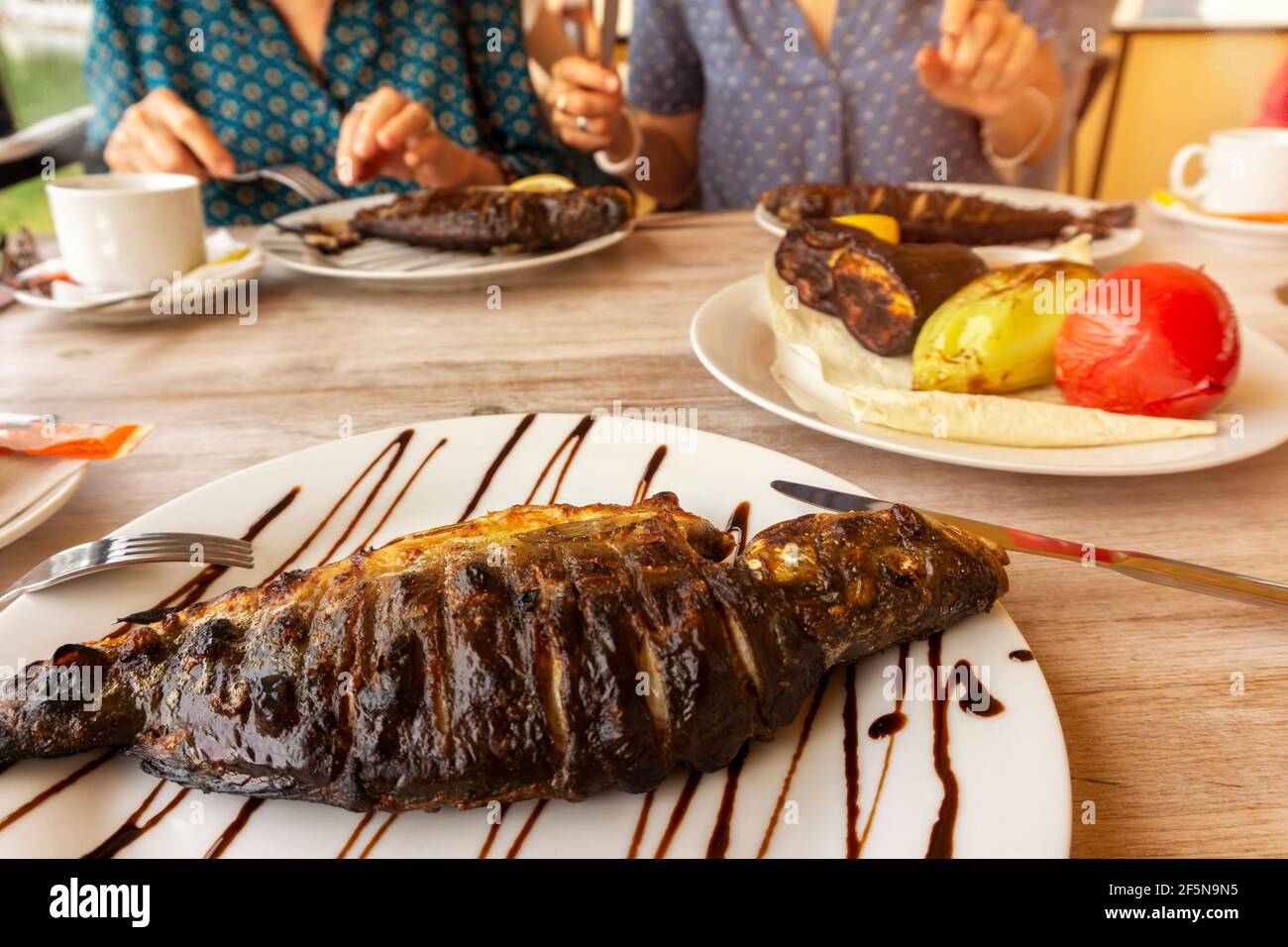 fried carp on a plate with baked vegetables. Concept - people eat in a ...