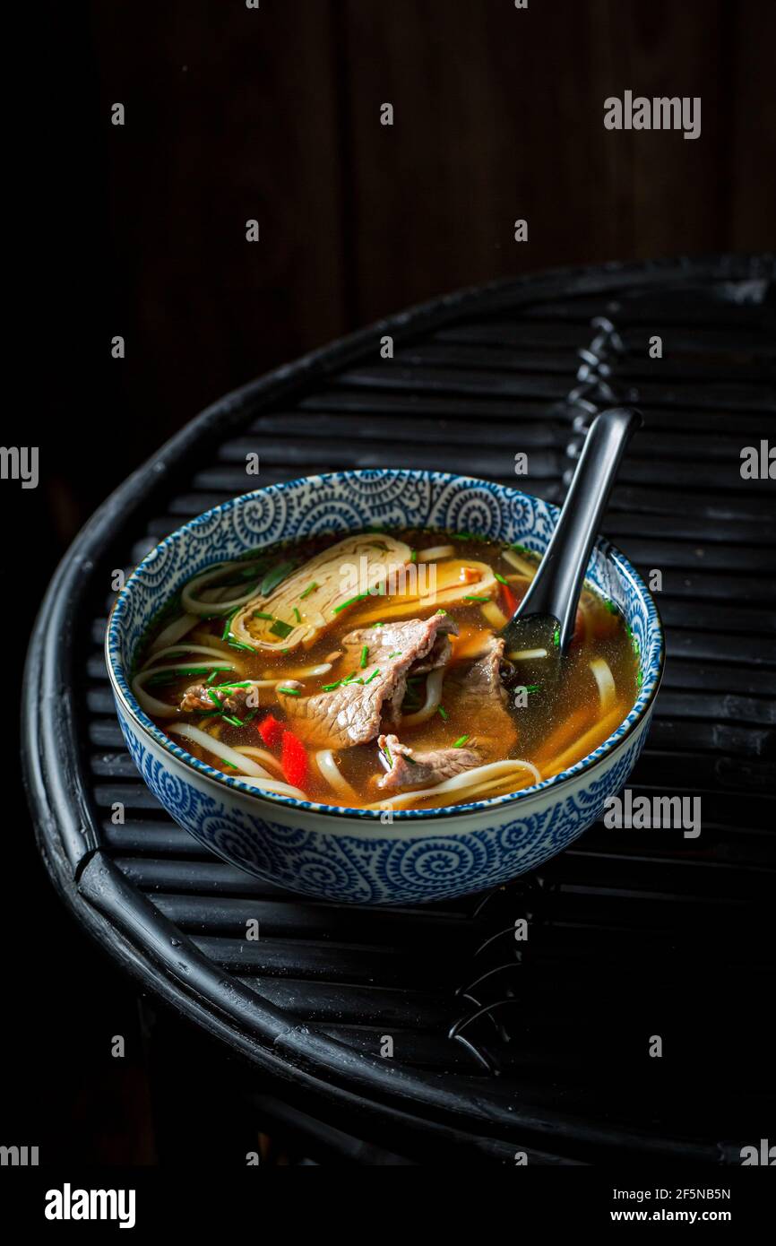 Tasty Thai broth with beef and noodle on black background. Traditional ...