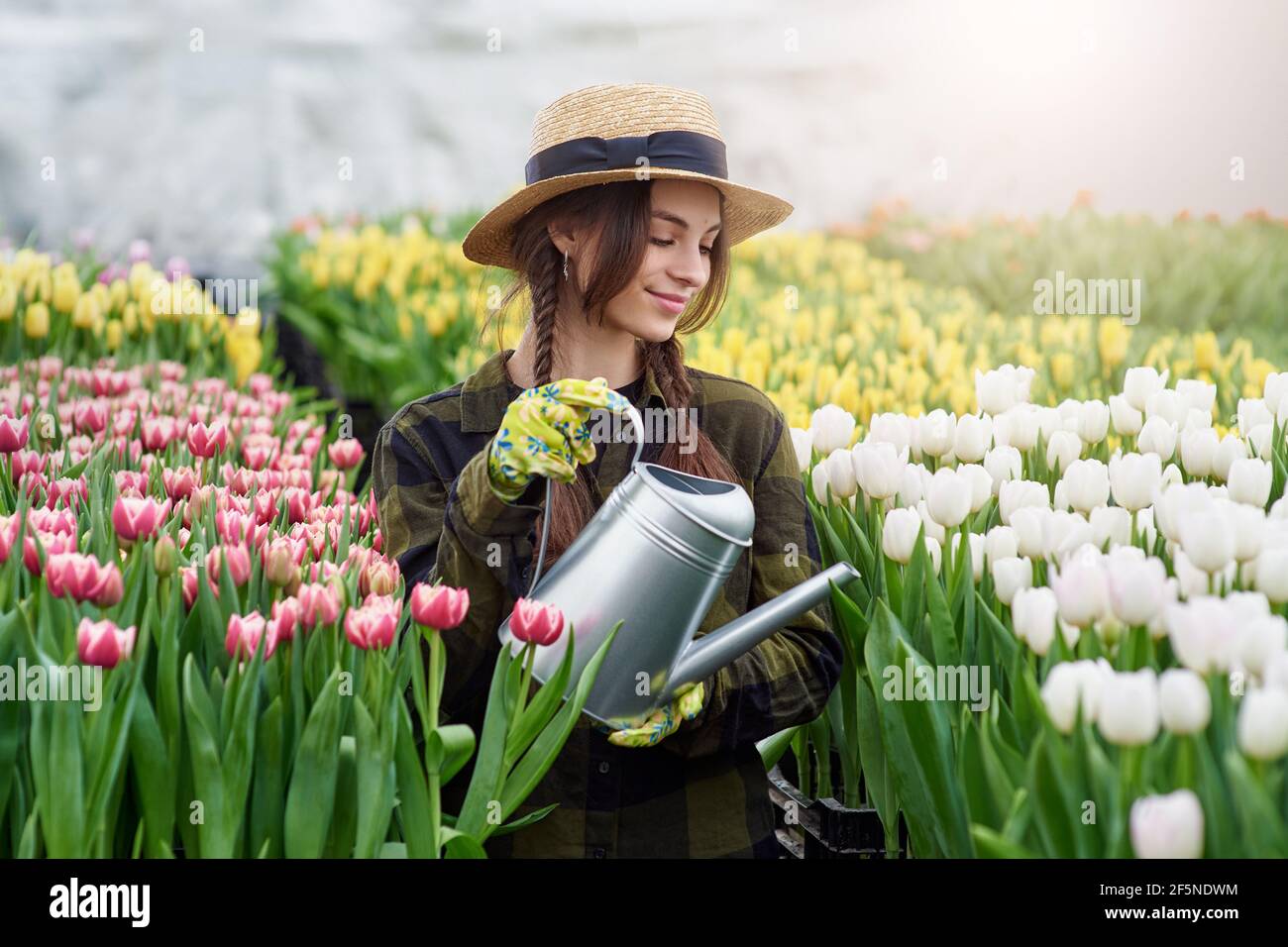 Happy smiling teenager girl in hat with watering can in blossoming ...