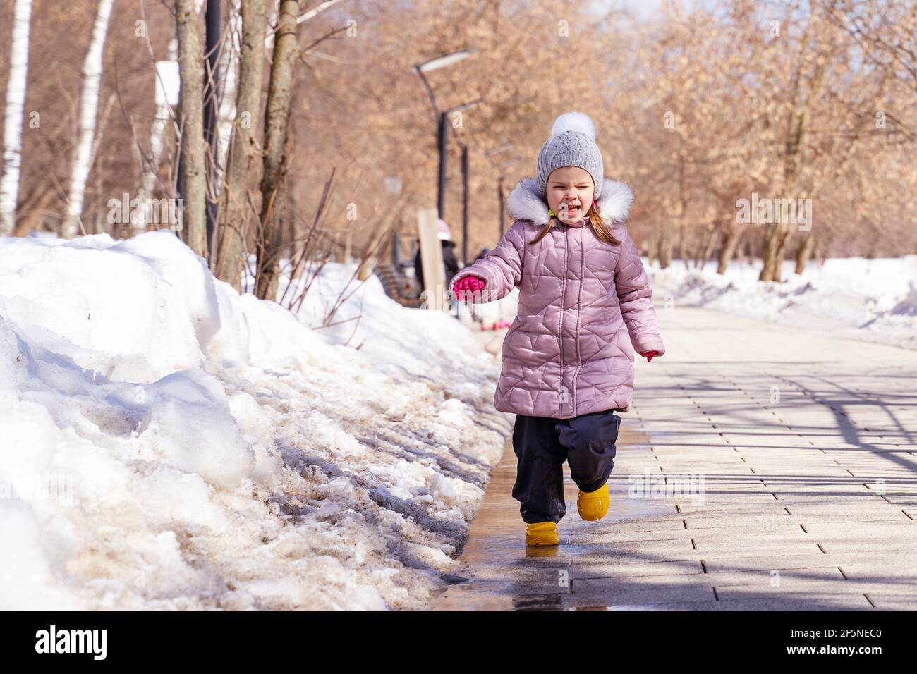 happy child girl jumping on spring puddles and laughing Stock Photo - Alamy