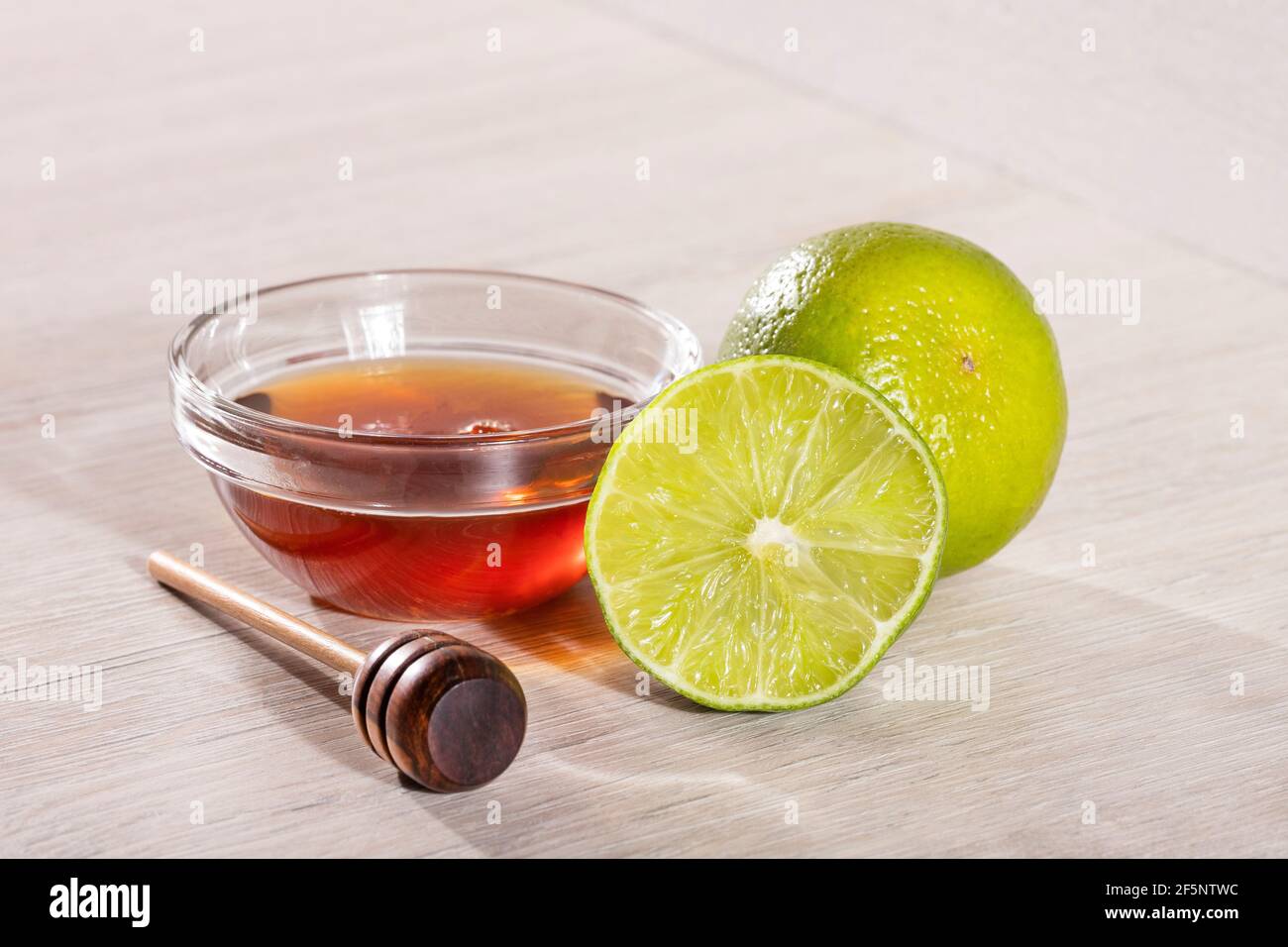 Honey in a glass bowl and lemon on the wooden table Stock Photo - Alamy