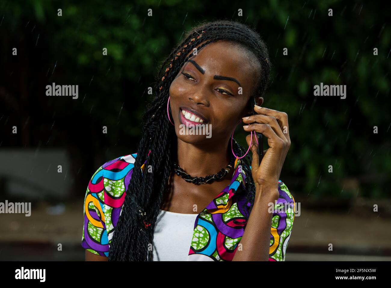 African girl standing under a fine rain communicating smiling Stock ...