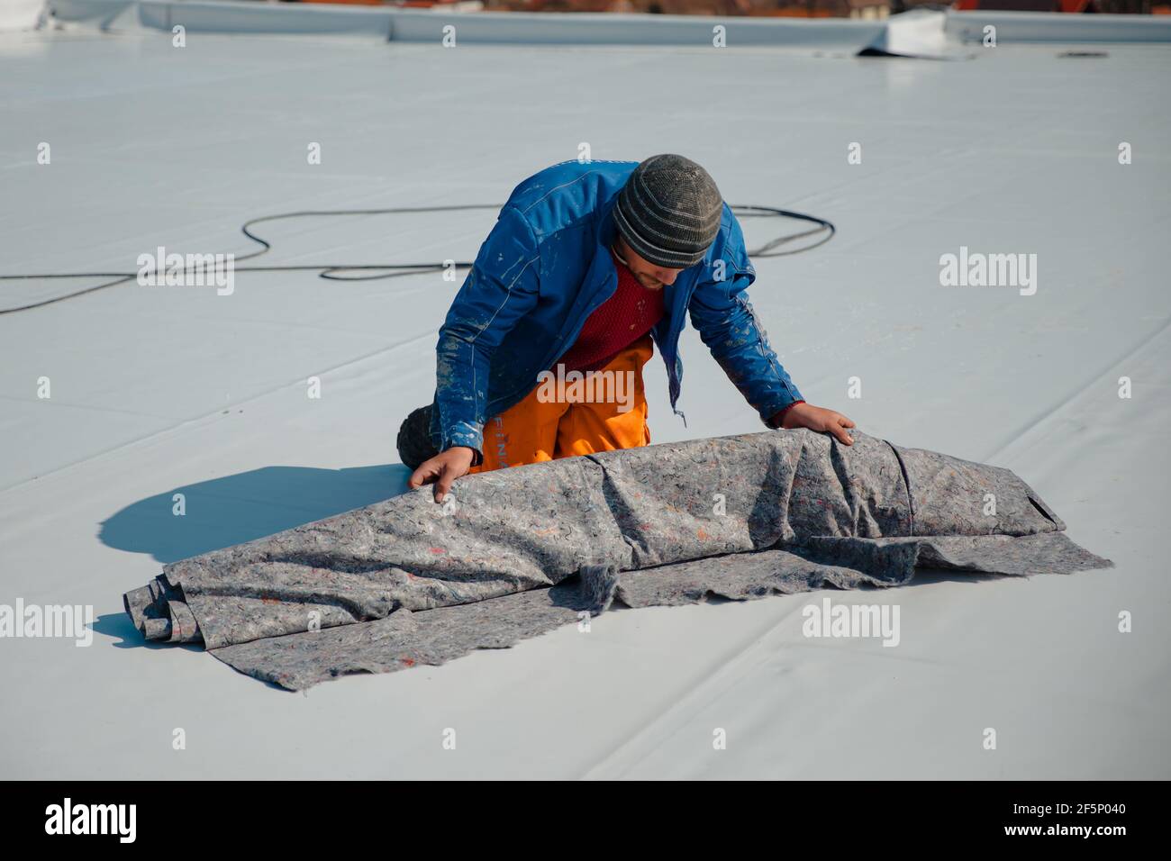Worker prepares geotextile for the roof, covers it with synthetic PVC ...