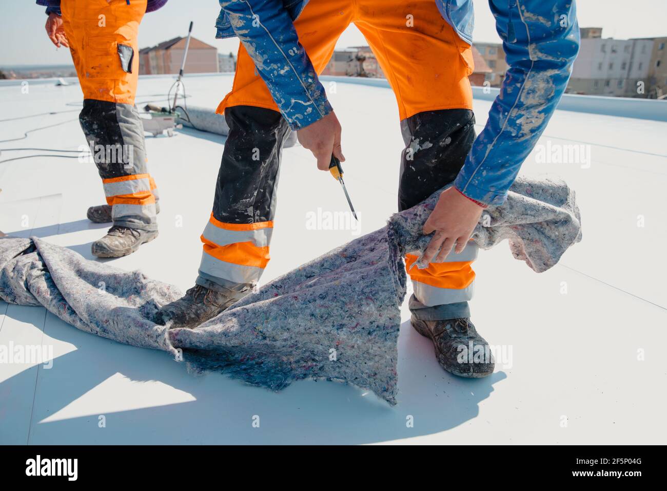 Worker prepares geotextile for the roof, covers it with synthetic PVC ...