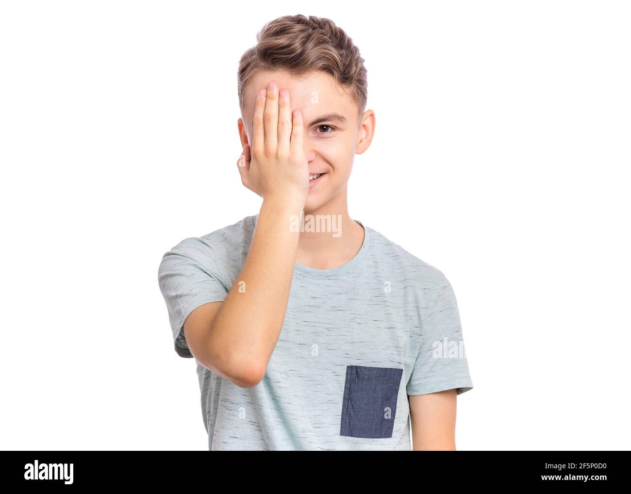 Handsome teen boy looks with one eye while covering his other eye with ...