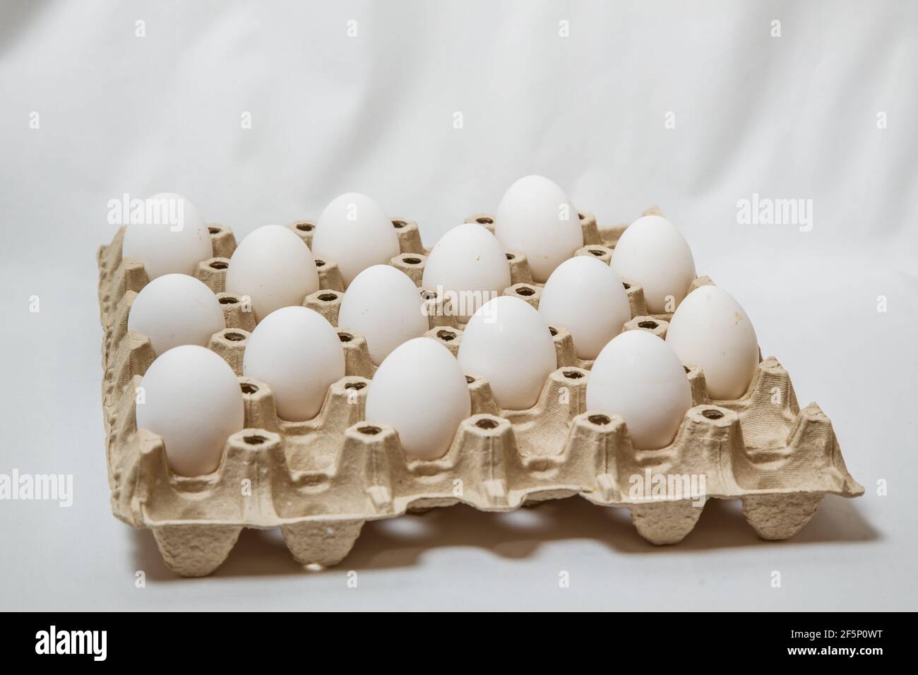 close up of carton box with distanced white eggs on white background ...