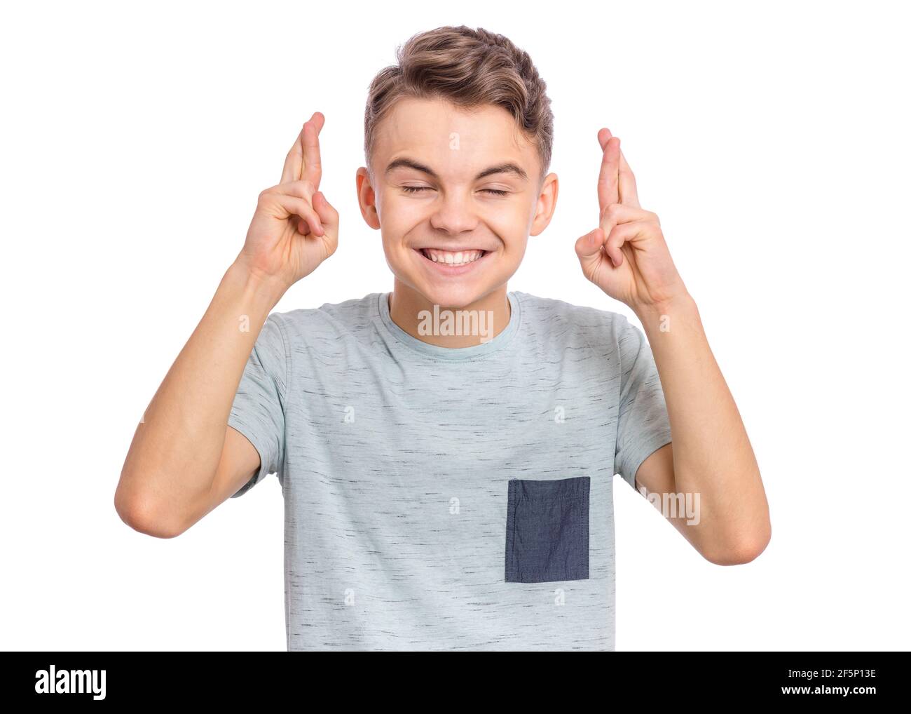 Handsome teen boy looking very happy holding fingers crossed for good ...