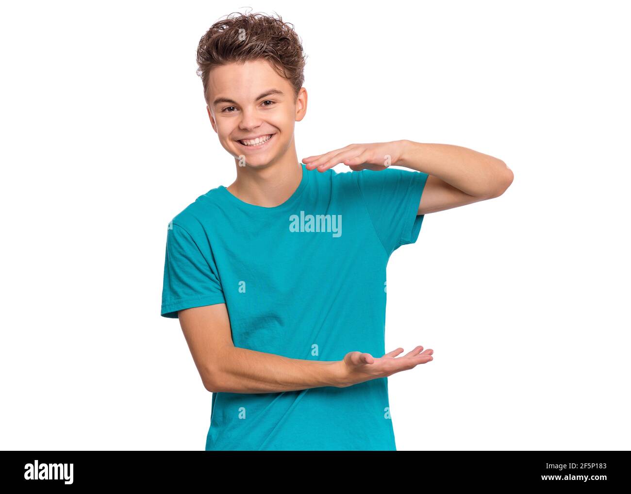 Handsome teen boy shows something in his hands and looking at camera ...
