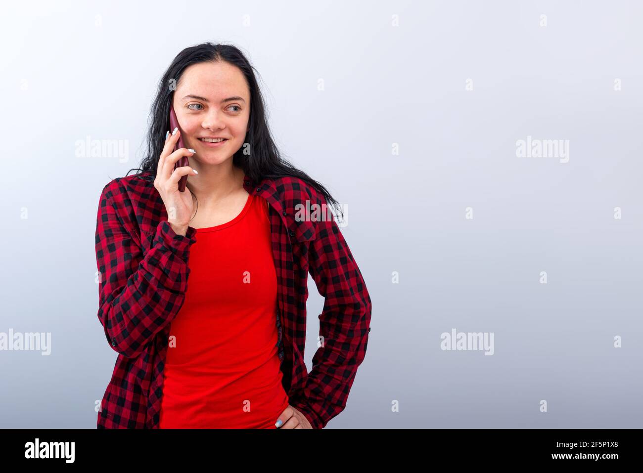 dark-haired emotional young woman in a red clothes talk on mobile phone ...
