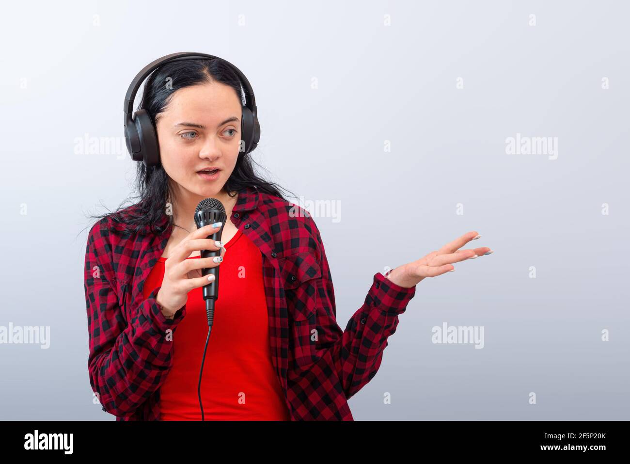expressive female singing with a microphone and headphones, isolated on ...
