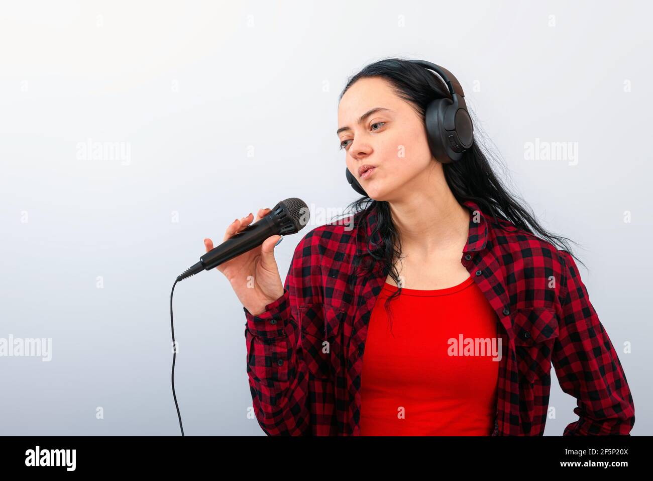 expressive female singing with a microphone and headphones, isolated on ...