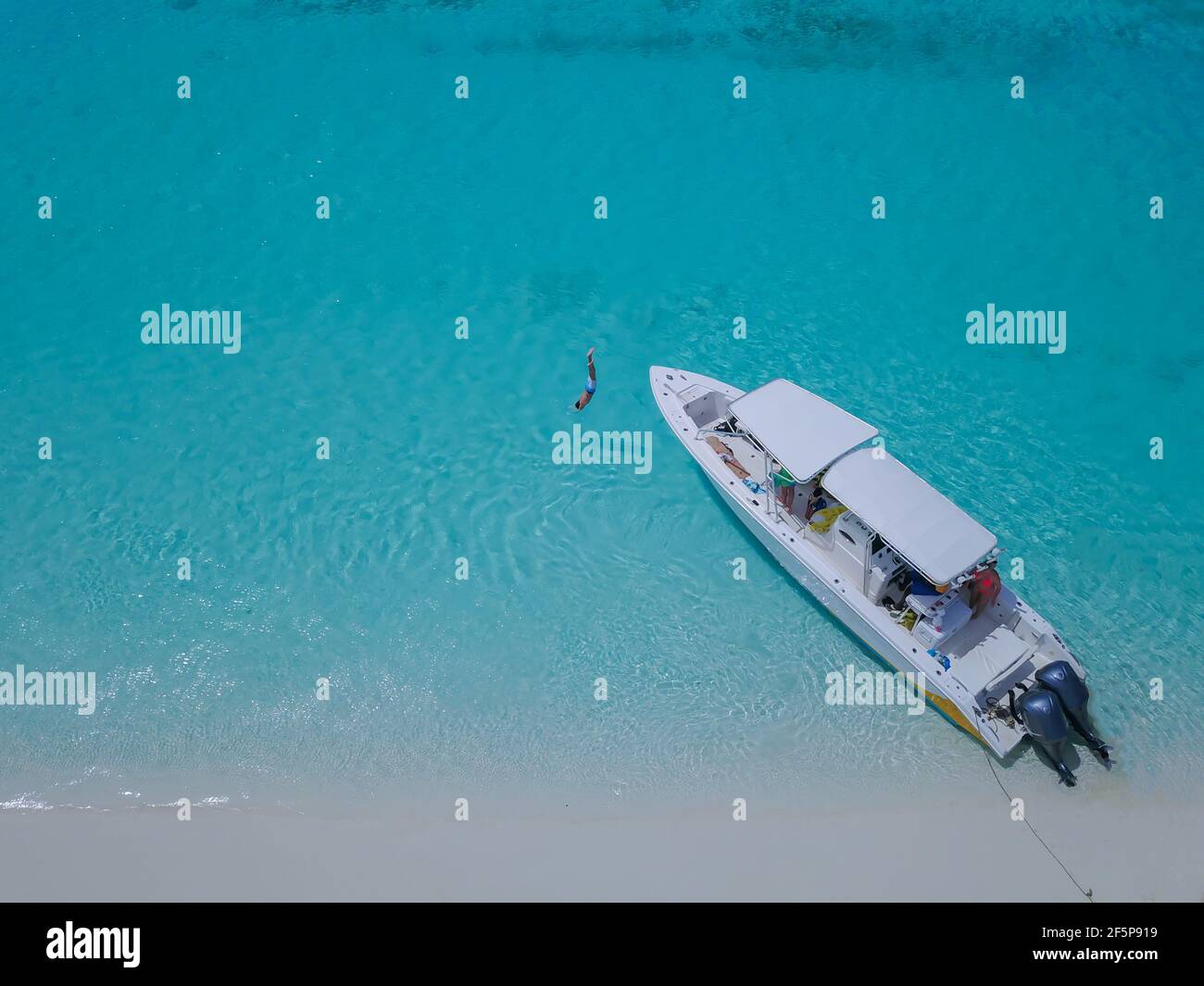 High angle shot of a boat with a person diving in the blue water, in ...