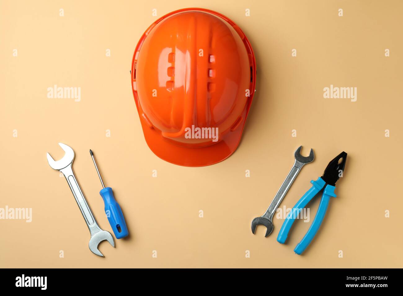 Hard hat and tools on beige background Stock Photo - Alamy