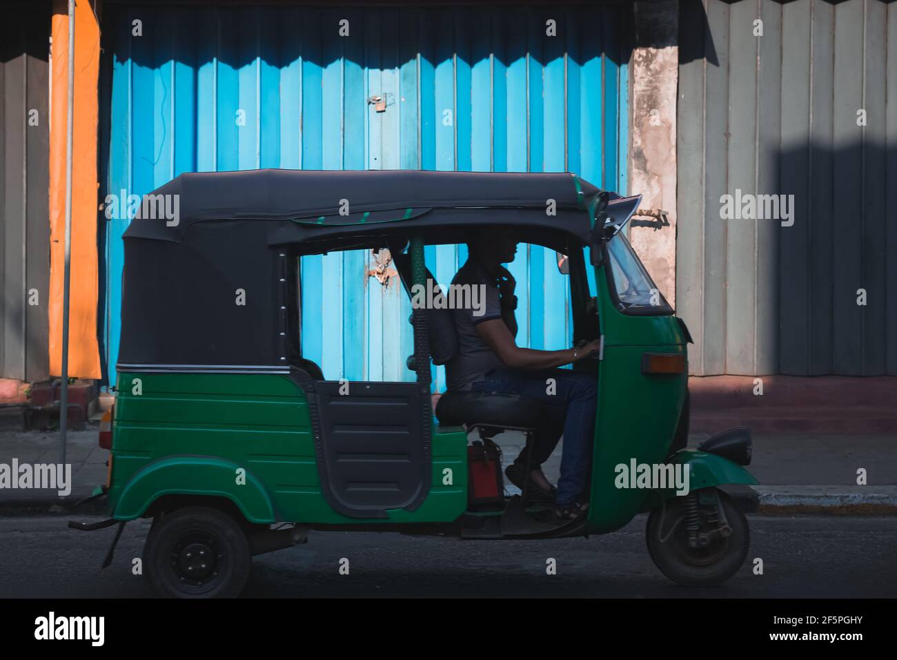 Silhouette of a local Sri Lankan auto rickshaw driver in with light and ...