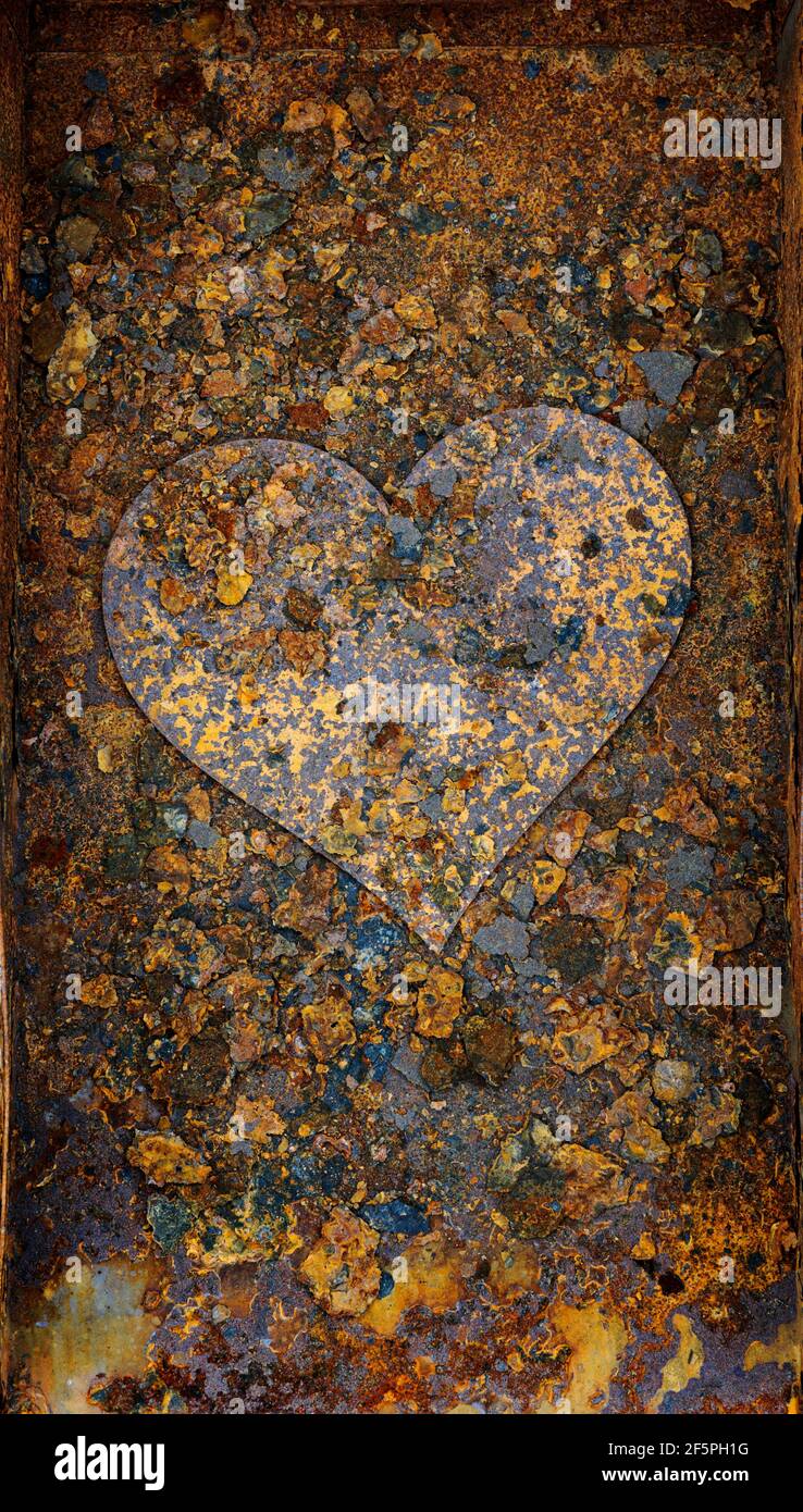 Rusty metal heart on corroded and rusting steel ash pan. After years of ...
