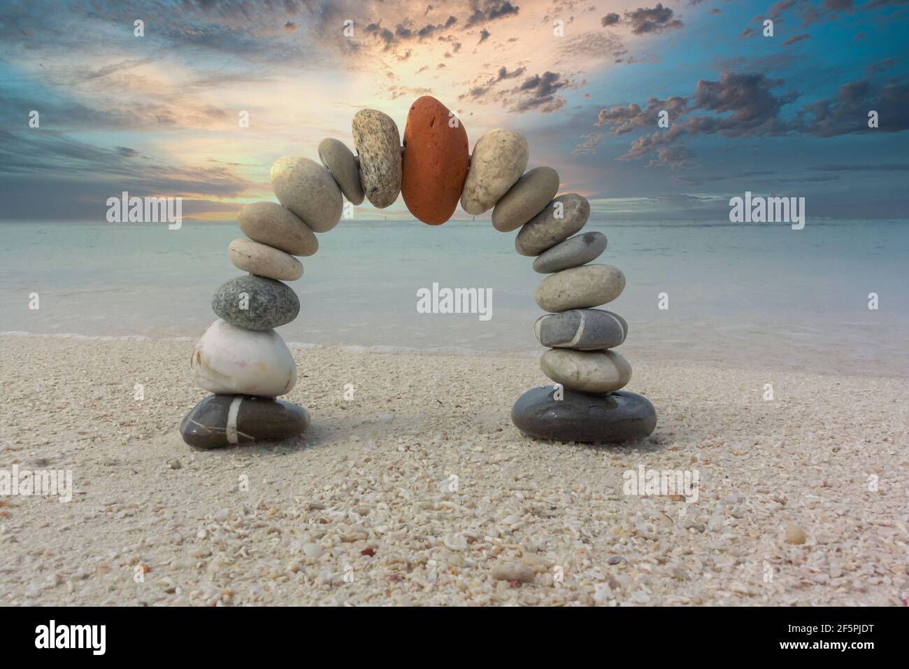 Closeup of a stone arch on a beach with a red one in the middle, the ...