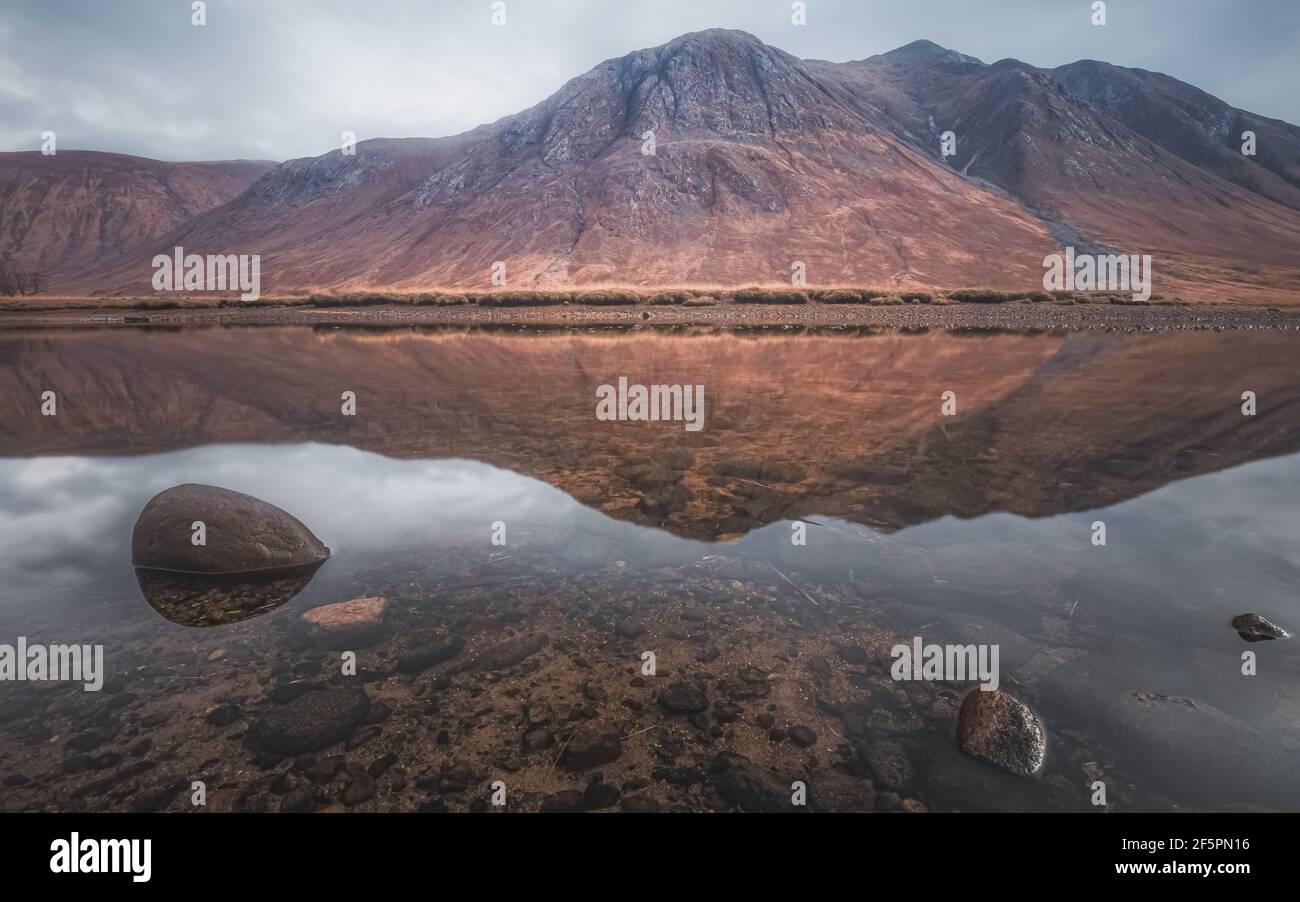 A moody Scottish Highlands landscape of a mountain reflection at Loch ...