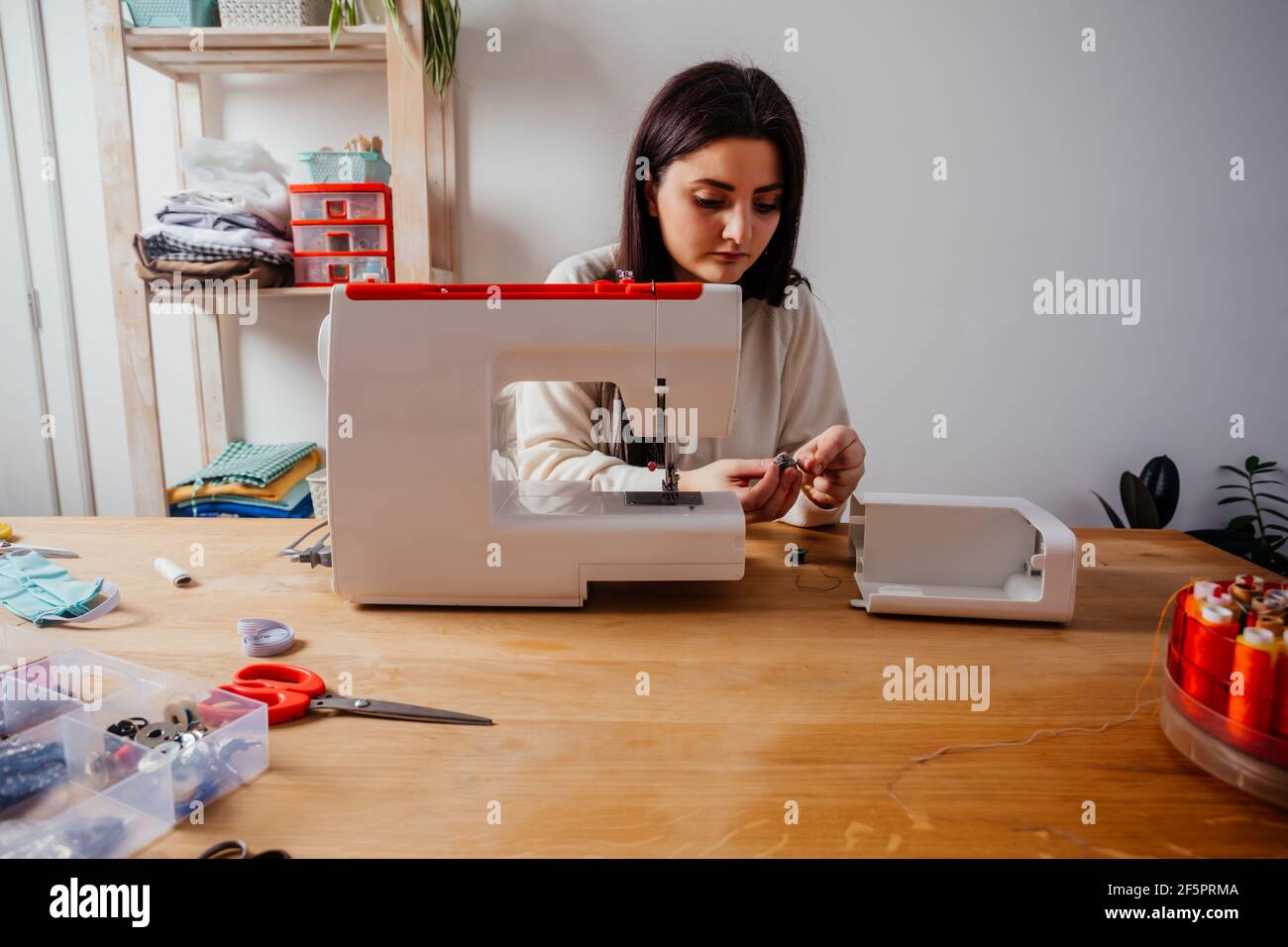 Woman hands filling thread into sewing machine spool Stock Photo - Alamy