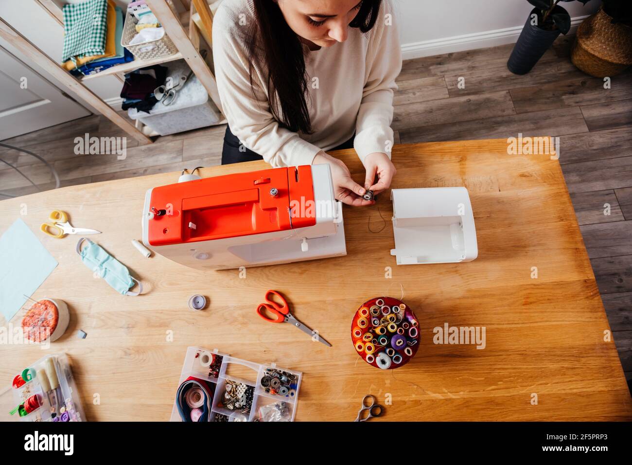 Woman hands filling thread into sewing machine spool Stock Photo - Alamy