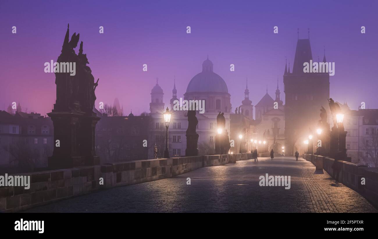 A quiet Gothic Charles Bridge at dawn with a moody, foggy atmosphere in old town Prague, Czech ...