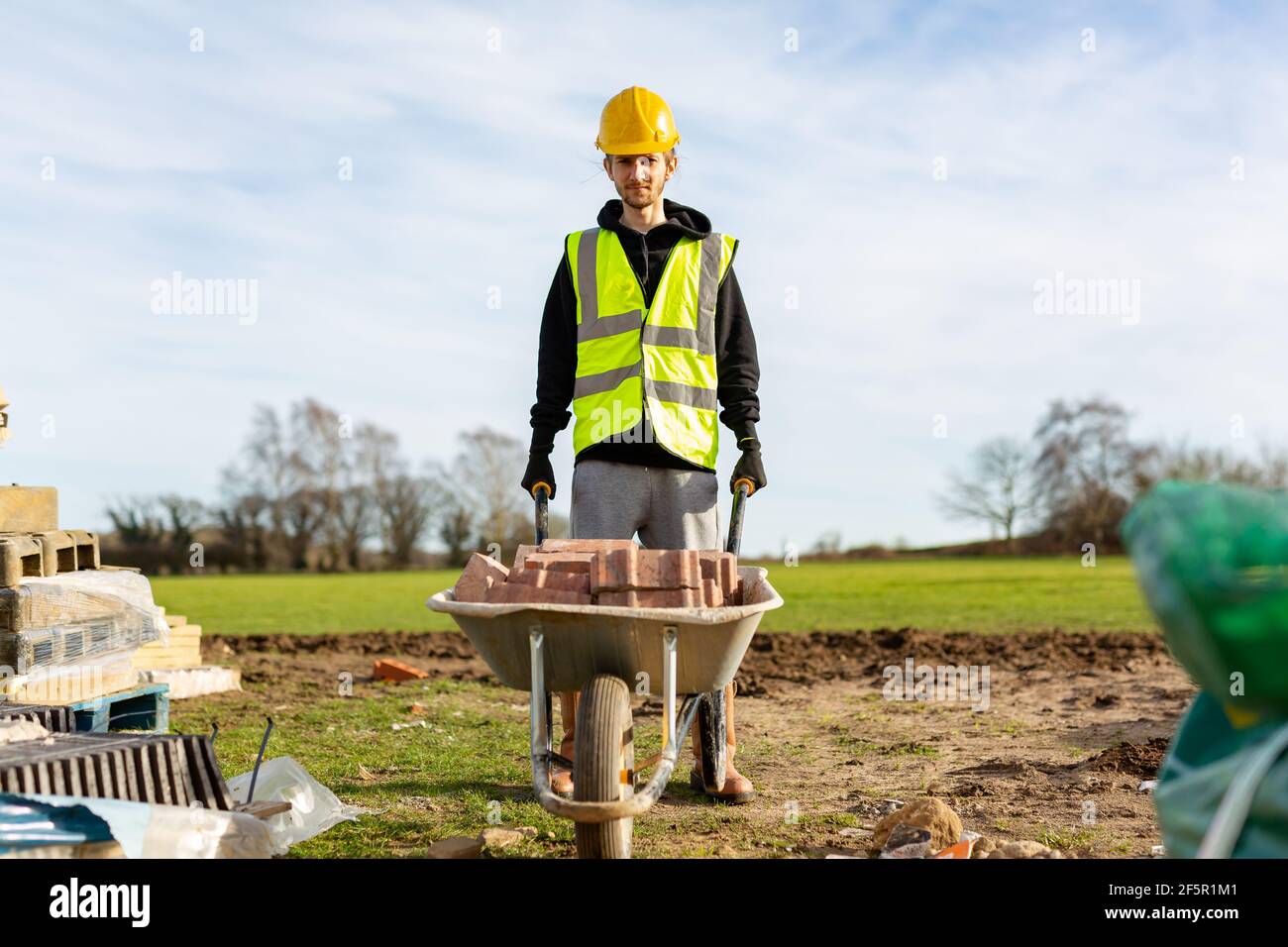 A young adult male builder wearing a high visibility vest and hard hat ...