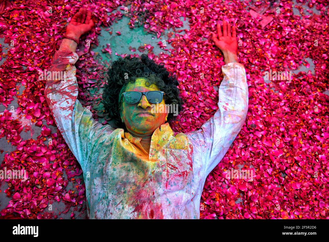 Mathura, India. 24th Mar, 2021. A man lies over the flower petals at ...