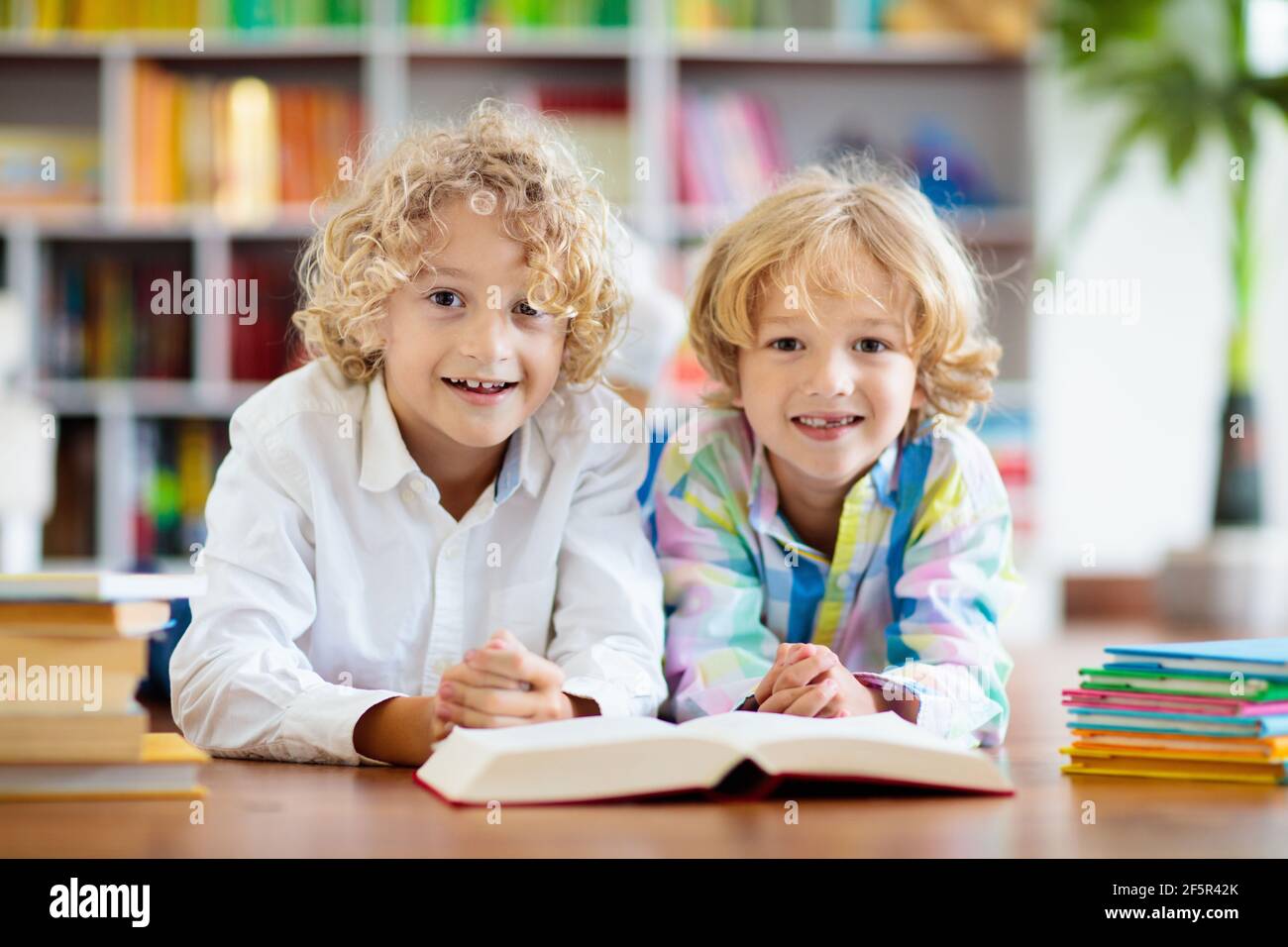 Child reading book. Kids read. Little boy at a colorful bookshelf doing ...
