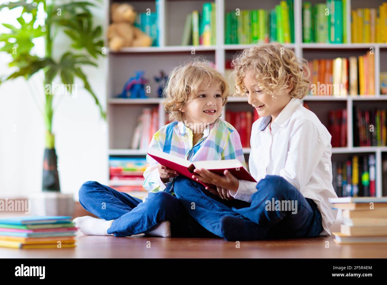 Child reading book. Kids read. Little boy at a colorful bookshelf doing ...