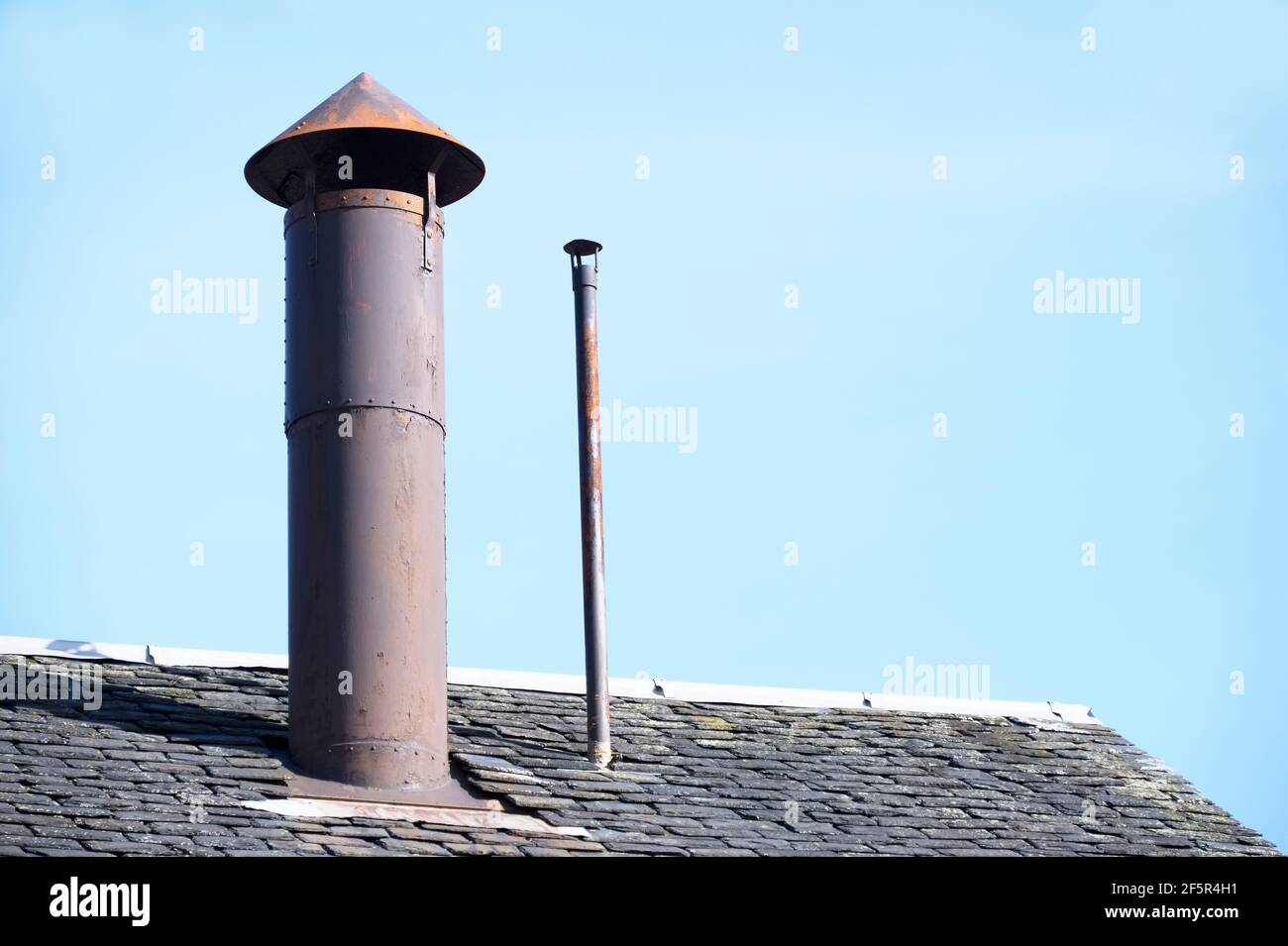 Flue chimney fixed to building exterior slate roof Stock Photo - Alamy