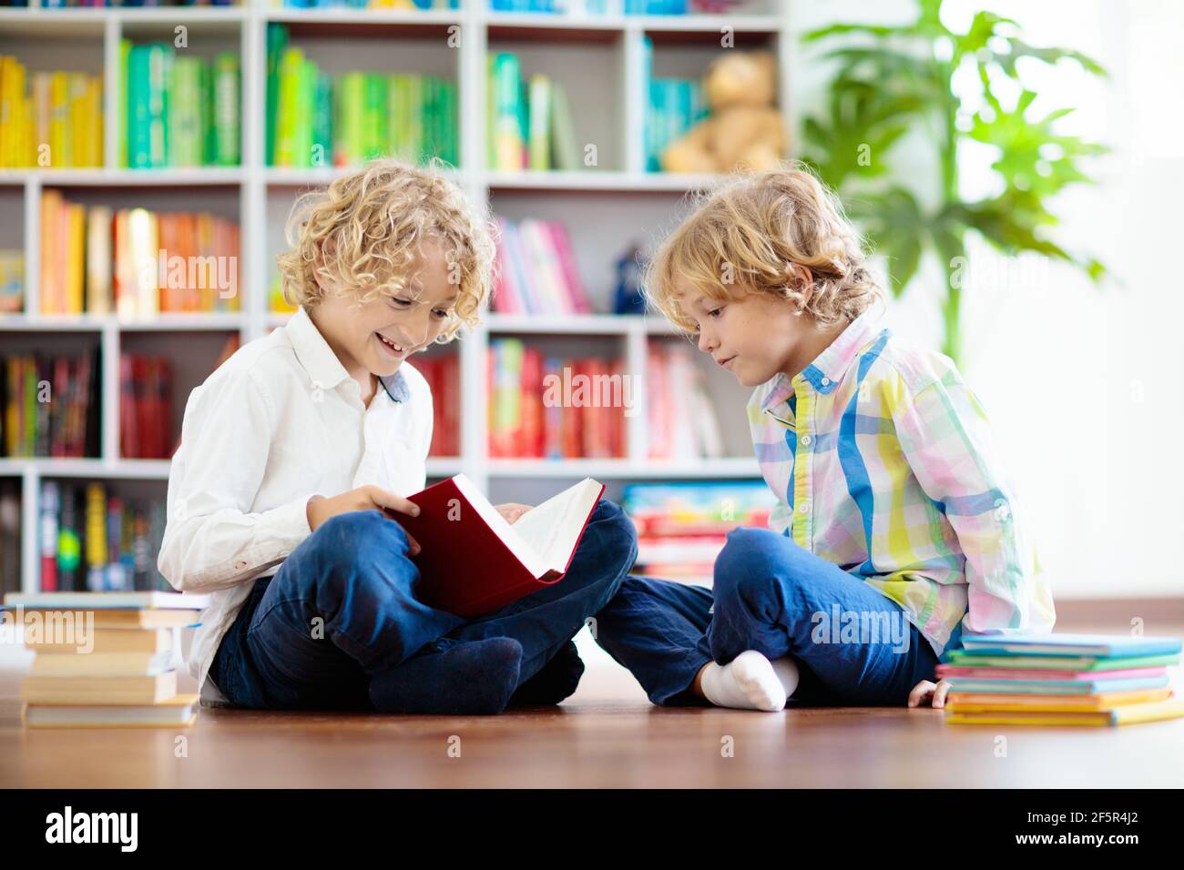 Child reading book. Kids read. Little boy at a colorful bookshelf doing ...