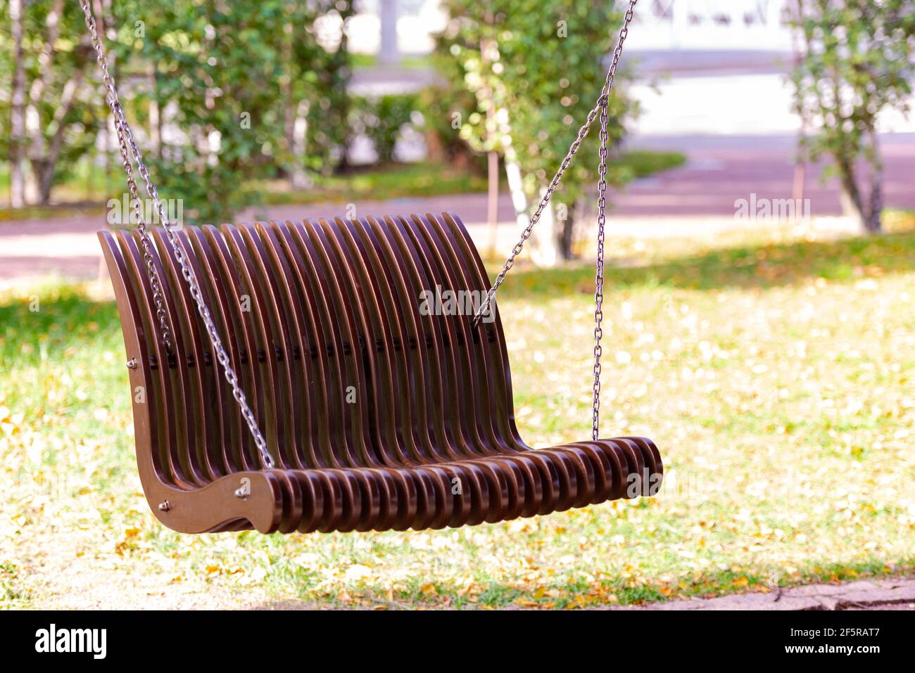 A bench suspended by chains. Air bench made of wooden parts. Summer and ...