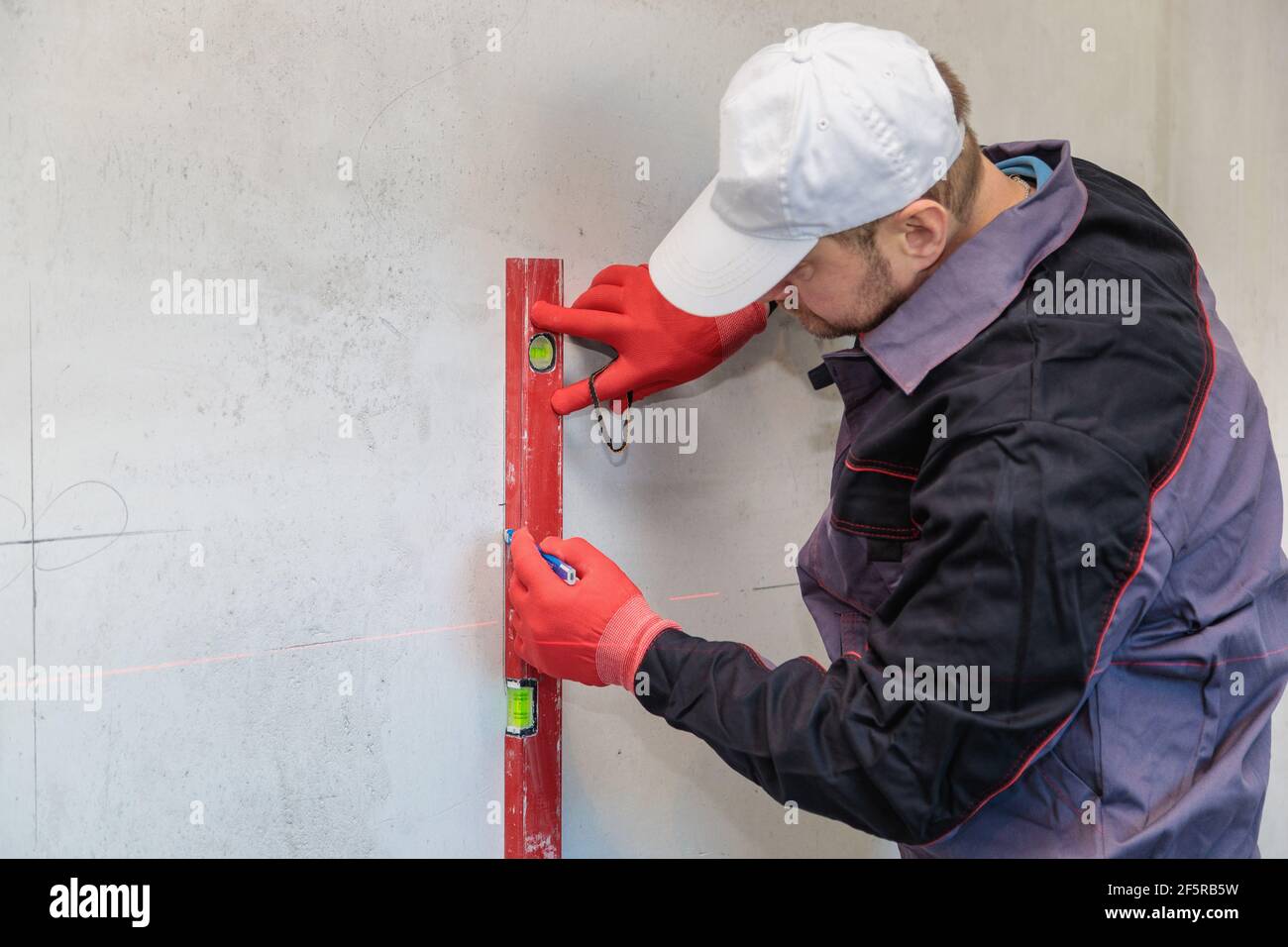 A man, an electrician marks out with a pencil, tape measure and a ...