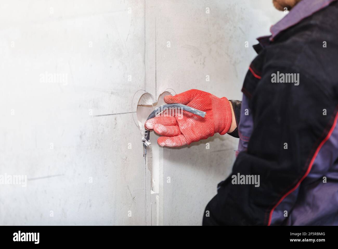 An electrician is laying a cable in an electrical ditch. Apartment ...