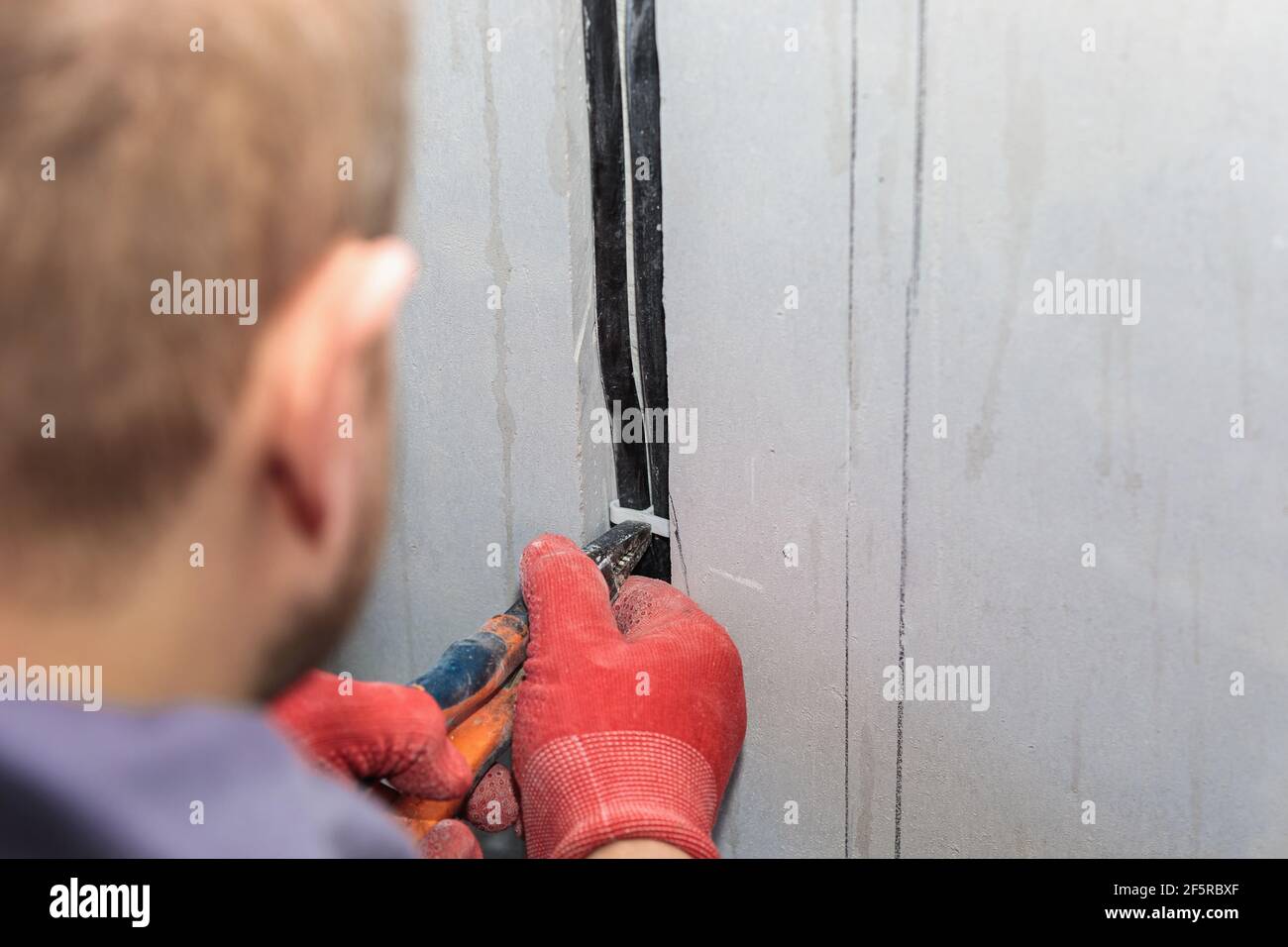 An electrician is laying a cable in an electrical ditch. Apartment ...
