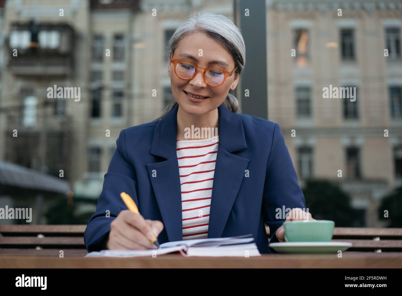Portrait of middle aged asian writer taking notes. Mature businesswoman ...