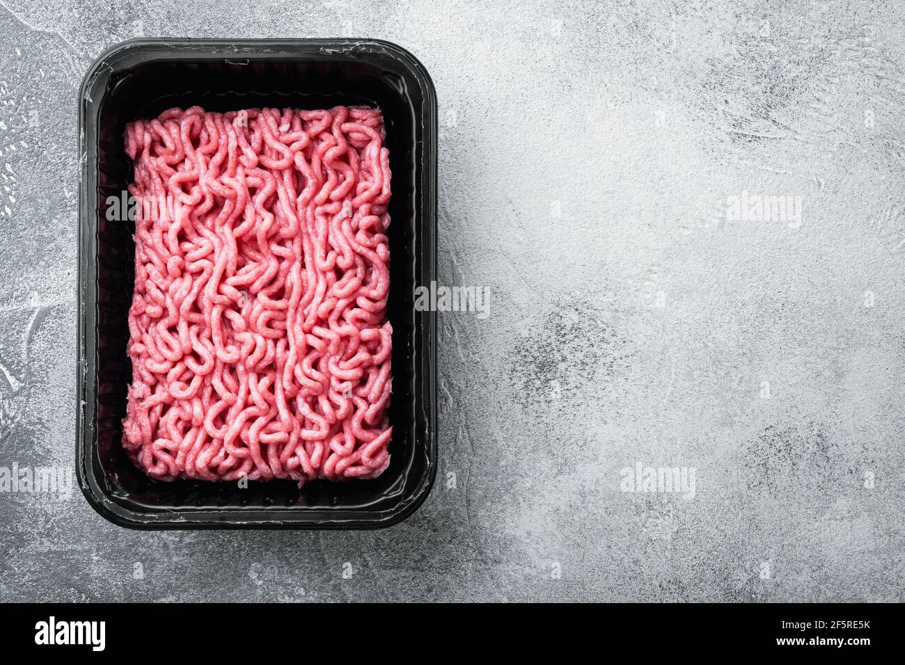 Fresh minced meat in plastic box packaging tray set, on gray stone ...