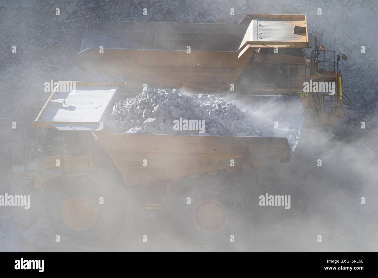 Dusty conditions as digger loads dump truck with ore at gold mine in ...